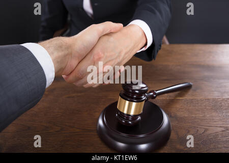 Close-up Of A Client And Judge Shaking Hands With Each Other Near Gavel ...