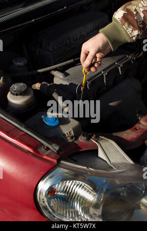 A car engine oil dipstick is being used to check the oil level Stock Photo - Alamy