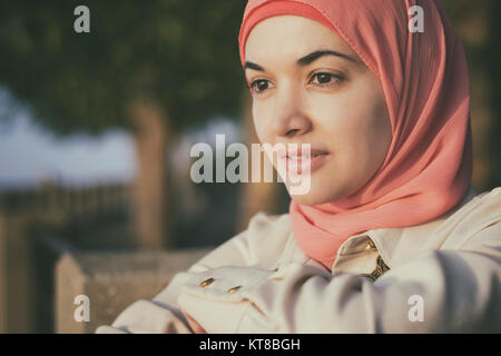 Beautiful Muslim woman leaning on the fence looking away outdoors Stock ...