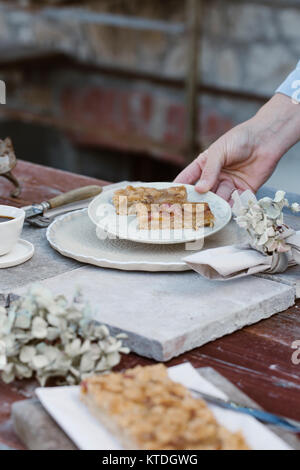 Italy, woman laying breakfast table on terrace Stock Photo - Alamy