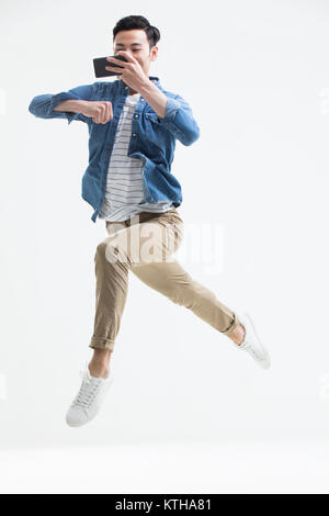 Young man jumping with a smart phone Stock Photo - Alamy