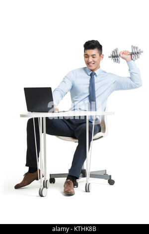 Young businessman lifting weights while using computer at work Stock ...