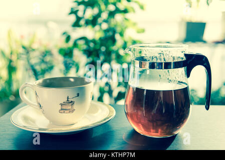 Composition with cup of green tea, teapot and dry leaves on dark ...
