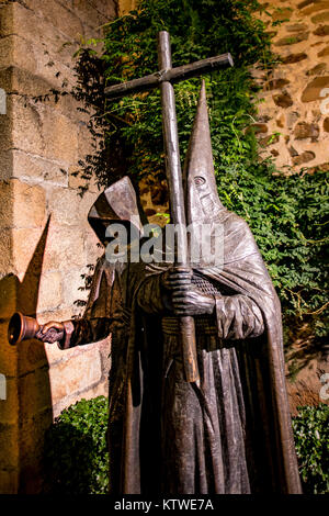 Statue of a penitent (Nazareno) in a pointed hood (capirote) carrying a ...