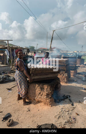Two women smoking fish over a clay oven, Jamestown Fishing Village ...