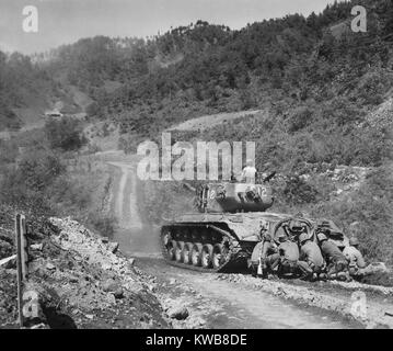 Marine infantrymen take cover behind a tank while it fires on Communist ...