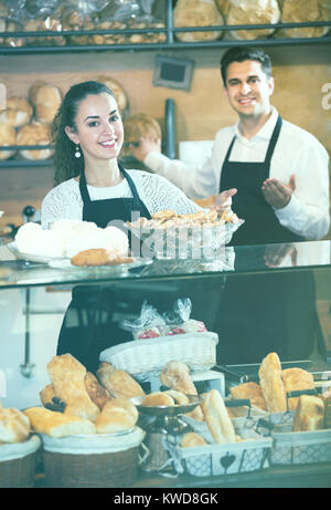 Happy women selling fresh pastry and loaves in bread section. Focus on ...