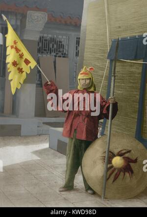 Chinese Boxer with shield and banner on urban street, c. 1900. The ...