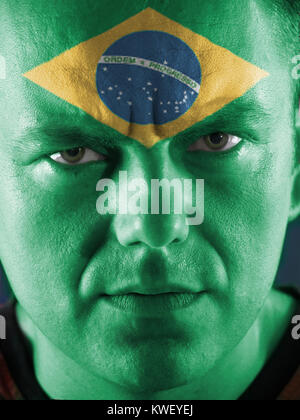 Brazilian fan with paint on his face celebrating on a blue lights ...