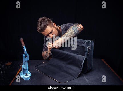 Leather handbag craftsman at work in a vintage workshop. Small business ...