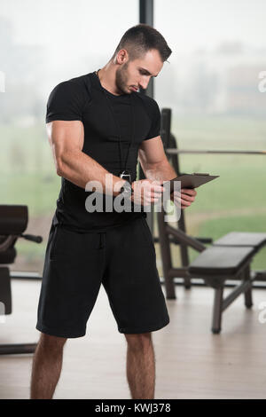 Personal Trainer Takes Notes On Clipboard In Fitness Center Gym Stock ...