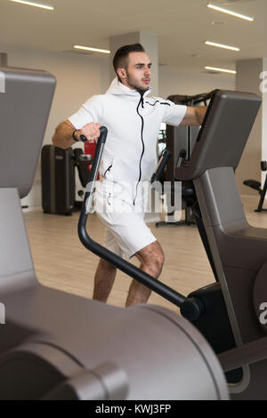 Muscular Man Doing Aerobics Elliptical Walker In Modern Fitness Center ...