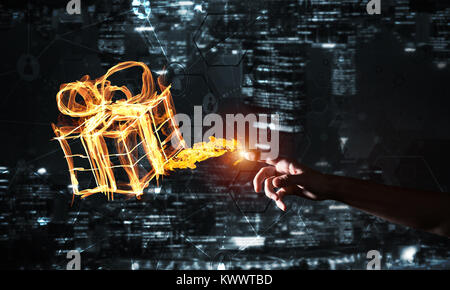 Glowing fire gift box icon in palm on dark background Stock Photo - Alamy