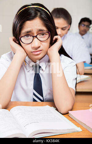 Sad student sitting in classroom with her head in hands. Education ...