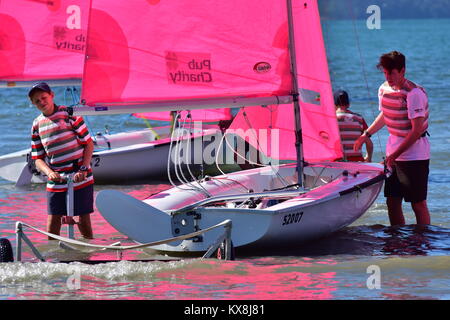 Launching 420 class sailing dinghy from hand trailer in shallow water ...