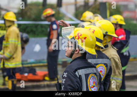Firefighters in protective gear stand in front of a damaged building ...