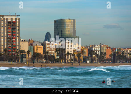 Surfers on waves with Barcelona skyline to the rear. Catalonia, Spain ...
