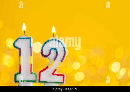 Number 12 birthday celebration candle against a bright lights and blue ...