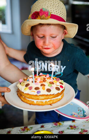 Boy blowing out candles on a birthday cake Stock Photo - Alamy