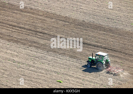 An aerial view of a tractor ploughing a fertile agricultural field with ...
