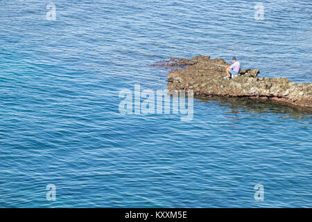 Man fishing from a rocky outcrop Stock Photo - Alamy