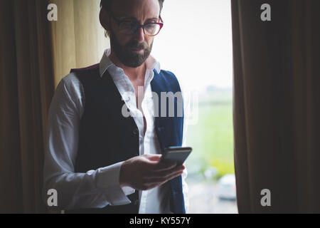 Businessman using mobile phone near office window at receptions area ...