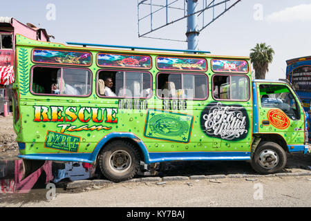 A brightly decorated bus with artwork waits by the side of the road ...