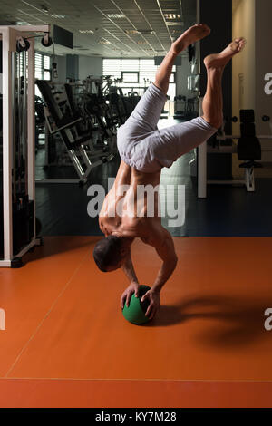 Athlete Doing Handstand Push-Ups On Medicine Ball As Part Of ...