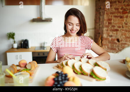 Young woman smiling and making sandwich in kitchen at home Stock Photo ...