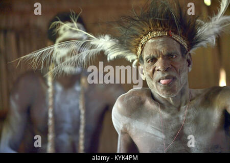 Portrait of a man from the tribe of Asmat people with a drum in the men ...