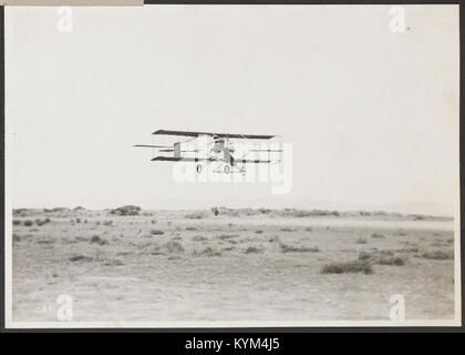 A Curtiss Pusher aircraft flying over a crowd of onlookers, showcasing ...