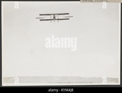 A historic photograph of a Curtiss Pusher biplane in flight at dusk ...