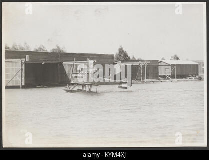 The Martin TT biplane in flight over a hangar, captured in an archival ...