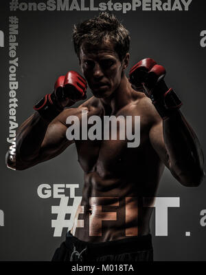 Male boxer with bare chest in boxing gloves sitting near red corner of ...