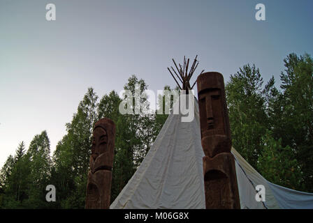 two heathen wooden totems in front of a traditional tent (chum or tipi ...