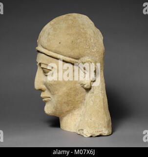 This limestone sculpture depicts a beardless male figure with a plain ...