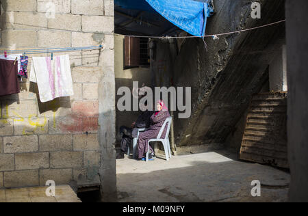 Palestinian refugees sit outside their home in the al-Shati refugee ...