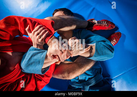 Close-up two wrestlers of grappling and jiu jitsu in a blue and red ...