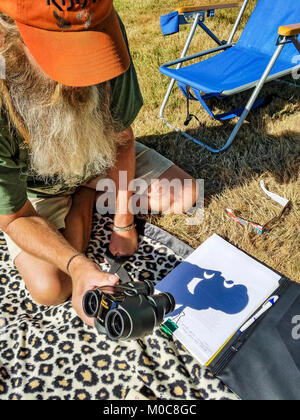 Man uses binoculars backwards to cast crescents of light on paper while ...