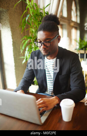 Young african american businessman typing a message on a phone while ...