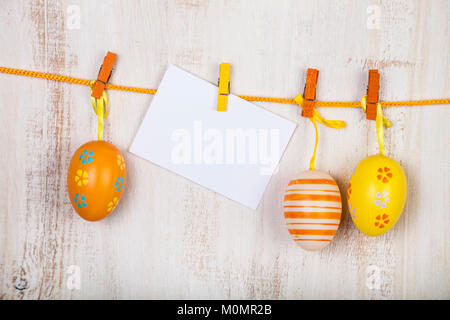 Easter Eggs, feathers and paper on a rope on a blue wooden background ...