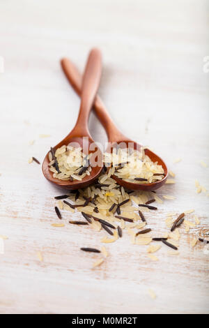 Mix of different varieties of rice in bowl on a wooden background ...