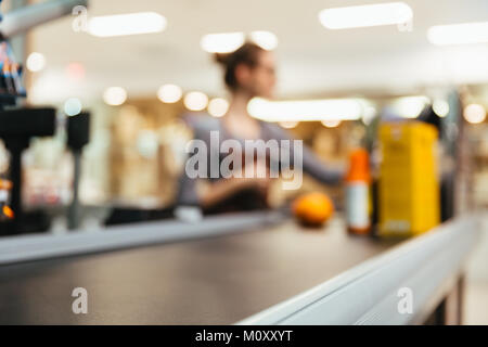 Woman cashier scanning grocery items at checkout counter. Woman working ...