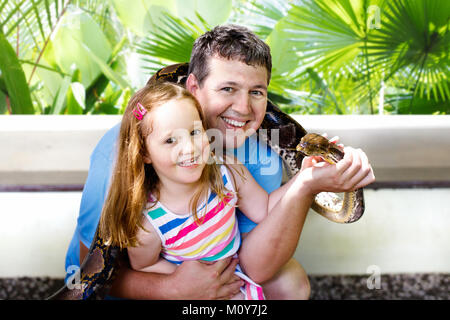 Kids holding python snake in tropical zoo. Children watching exotic ...