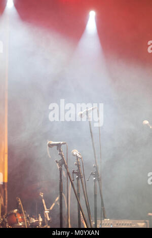 Microphone standing on a dark stage, illuminated by bright blue lights ...
