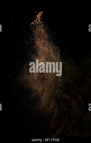 Cocoa powder explosion in motion. Chocolate dust on a black background ...
