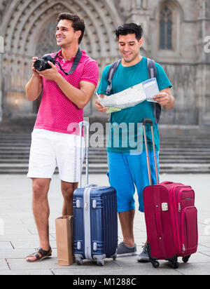 young men are walking with photocamera and searching way to historical ...