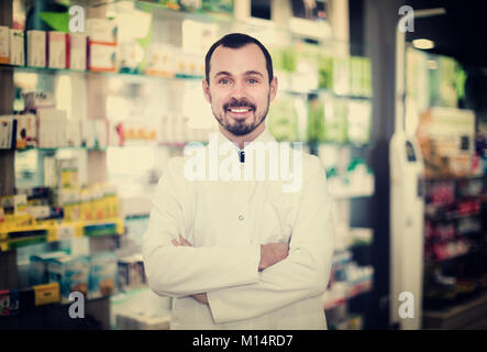 Smiling happy male pharmacist demonstrating assortment of drugs in ...