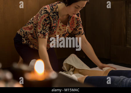 Professional therapist giving relaxing Thai oil leg massage treatment to a woman in spa Stock ...
