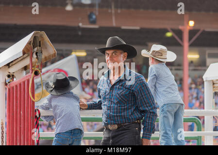 Rodeo cowboys stand behind chutes during a bronc riding competition at ...